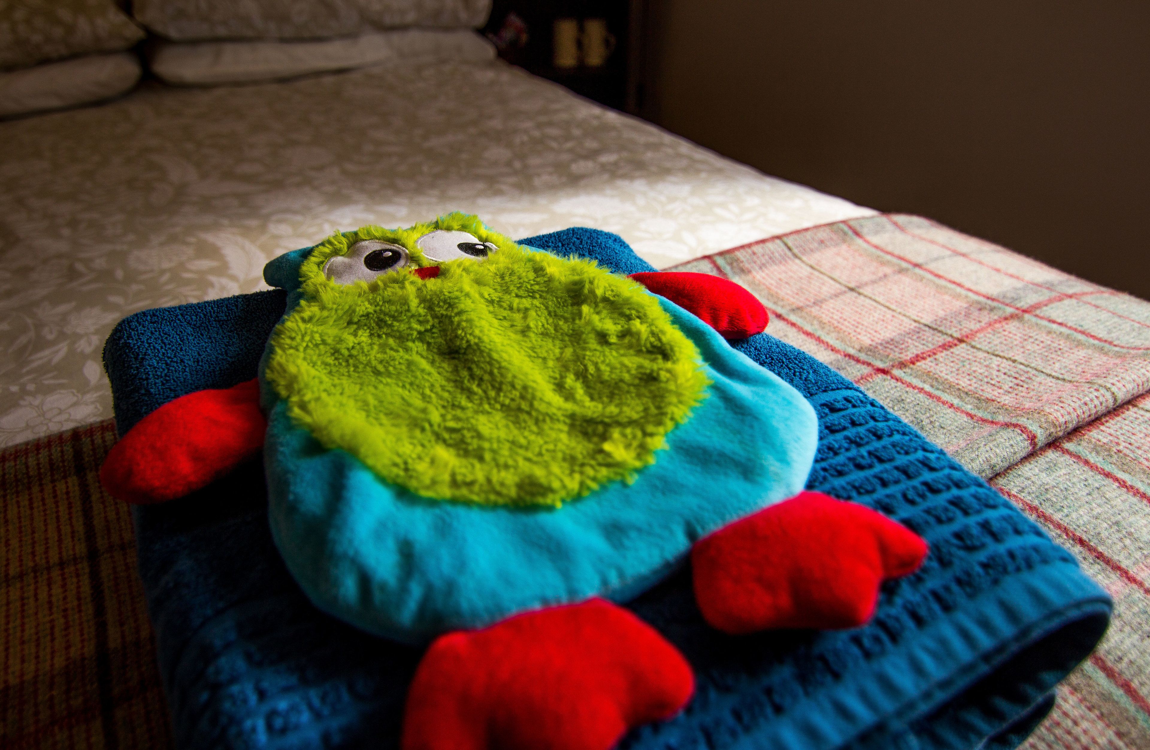 Um brinquedo macio em uma cama com colcha estampada.
