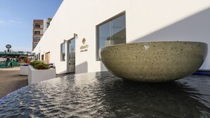 Um edifício moderno com uma tigela grande sobre uma superfície refletora, uma porta com um logotipo e uma placa indicando uma opção de comida saudável.