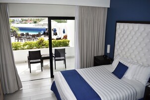 Quarto de hotel com uma cama, mesa de cabeceira, cadeira e vista para a área da piscina.