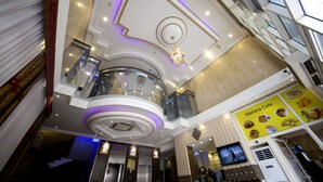 Um interior moderno com design circular central no teto, guarda-corrimão de vidro e um restaurante visível chamado "Mariana Cafe".
