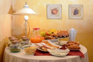 Um buffet de café da manhã com diversos alimentos, uma luminária e quadros nas paredes.