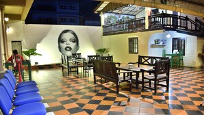Um pátio com piso xadrez, mesas ao ar livre e um mural.