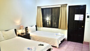 Quarto de hotel com duas camas, janela com cortinas, porta com aviso e mesa de cabeceira com abajur.