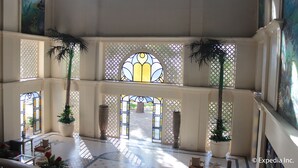 Um hall imponente com teto alto, amplas janelas e um arco central de vitrais.