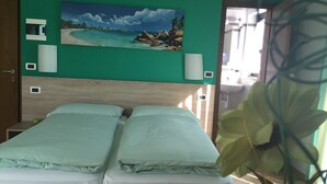 Quarto com uma cama, um quadro de uma praia, uma janela e uma planta.