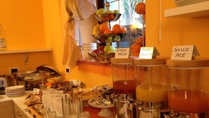 Buffet com diversos alimentos e bebidas, incluindo recipientes identificados para suco e sumo.
