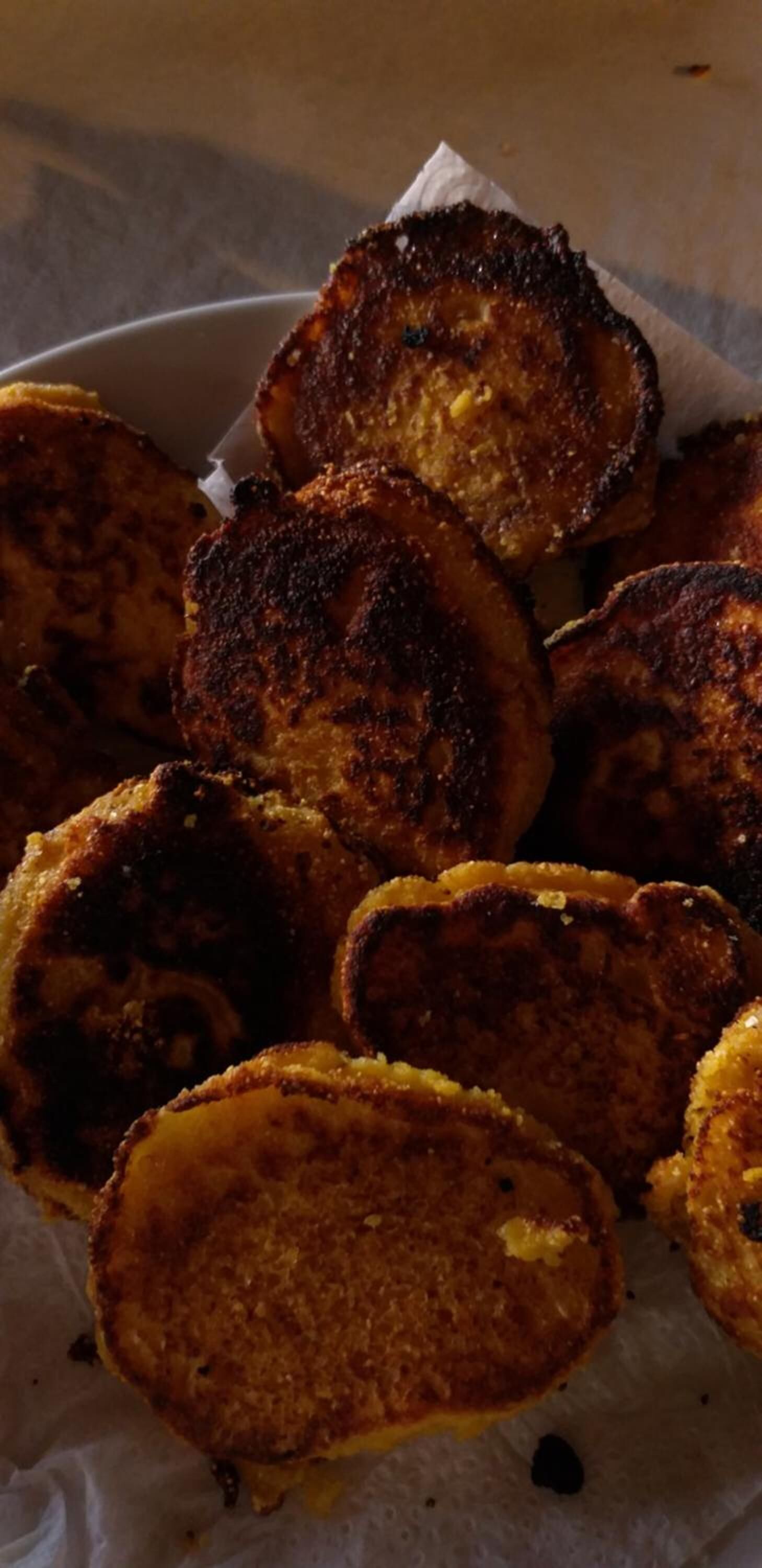 Um prato com itens fritos dourados, possivelmente bolinhos, em uma bandeja forrada com papel.