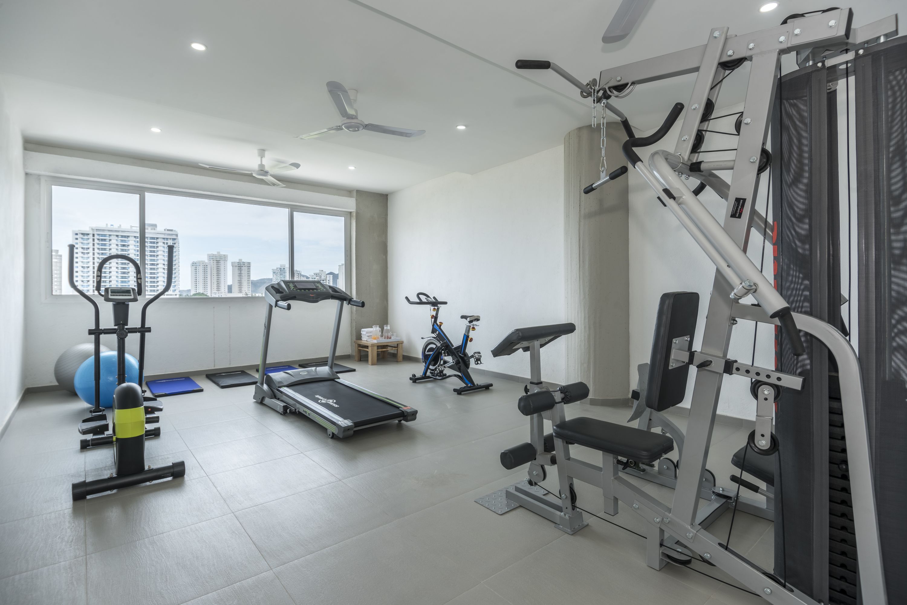 Uma academia com equipamentos de ginástica, esteira e bicicleta ergométrica.
