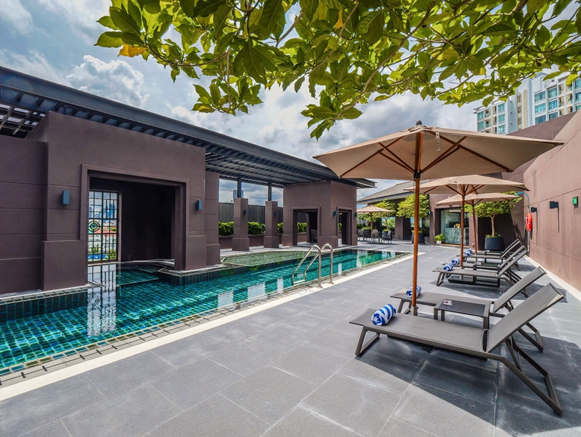 Uma área moderna com piscina ao ar livre, água azul cristalina, espreguiçadeiras e guarda-sóis.