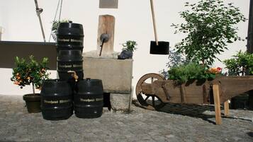 Barris externos, um carrinho de madeira e plantas em vasos à frente de uma parede de edifício.