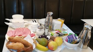 Uma mesa de café da manhã com pão, frutas e acompanhamentos.
