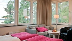 Quarto de hotel com duas camas, um sofá, uma pequena mesa e uma cadeira.