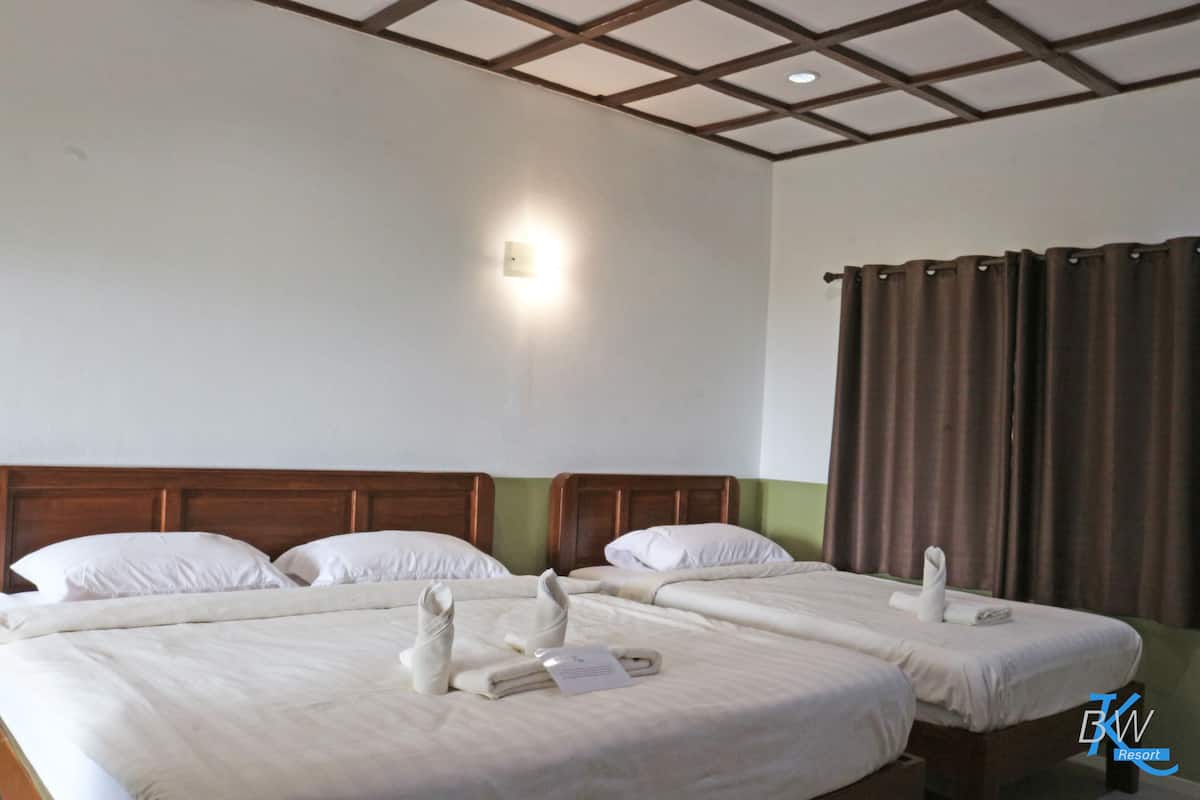 Quarto de hotel com duas camas, cabeceiras de madeira, roupa de cama branca e cortina à direita.