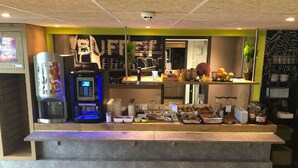 Cantinho de café com máquina de café, dispenser de água e diversas opções de alimentos.