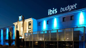 Um edifício com a placa "ibis budget" iluminada em azul.