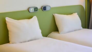 Quarto duplo com duas camas, cabeceira verde e luminárias laterais.