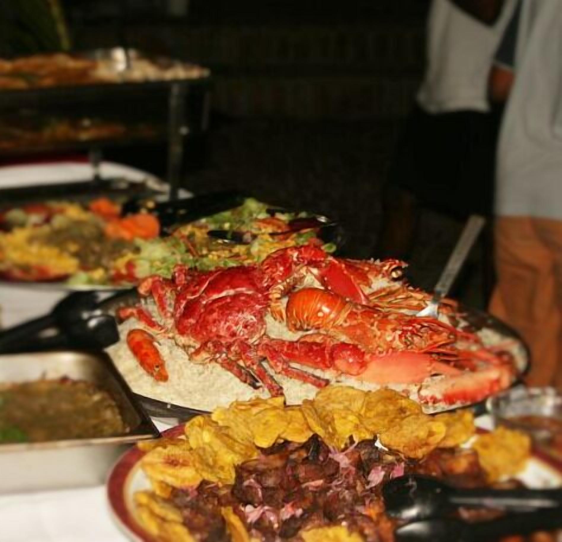 Buffet com diversos pratos, incluindo frutos do mar, legumes e outras opções.