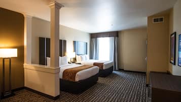 Quarto de hotel com duas camas, um espelho grande, uma TV de tela plana e uma escrivaninha.