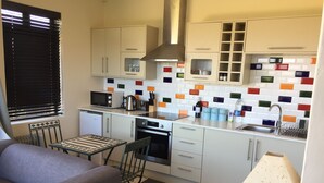 Uma cozinha compacta com área de refeições, equipada com micro-ondas, chaleira e pequeno frigorífico.