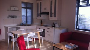 Um espaço compacto com cozinha compacta, área de refeições e sofá vermelho.