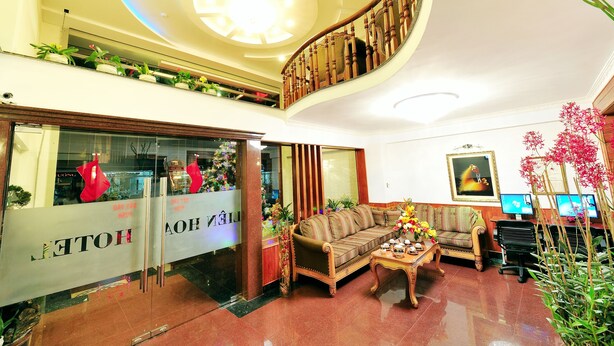 Um lobby de hotel com uma escadaria em curva, um sofá, uma mesa e uma janela grande.