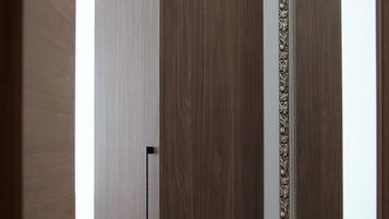 Quarto com guarda-roupa, um banquinho e um espelho com moldura decorada.