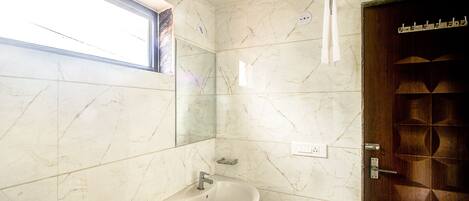 Casa de banho com parede de mármore, pia, espelho e porta de madeira com padrão geométrico.