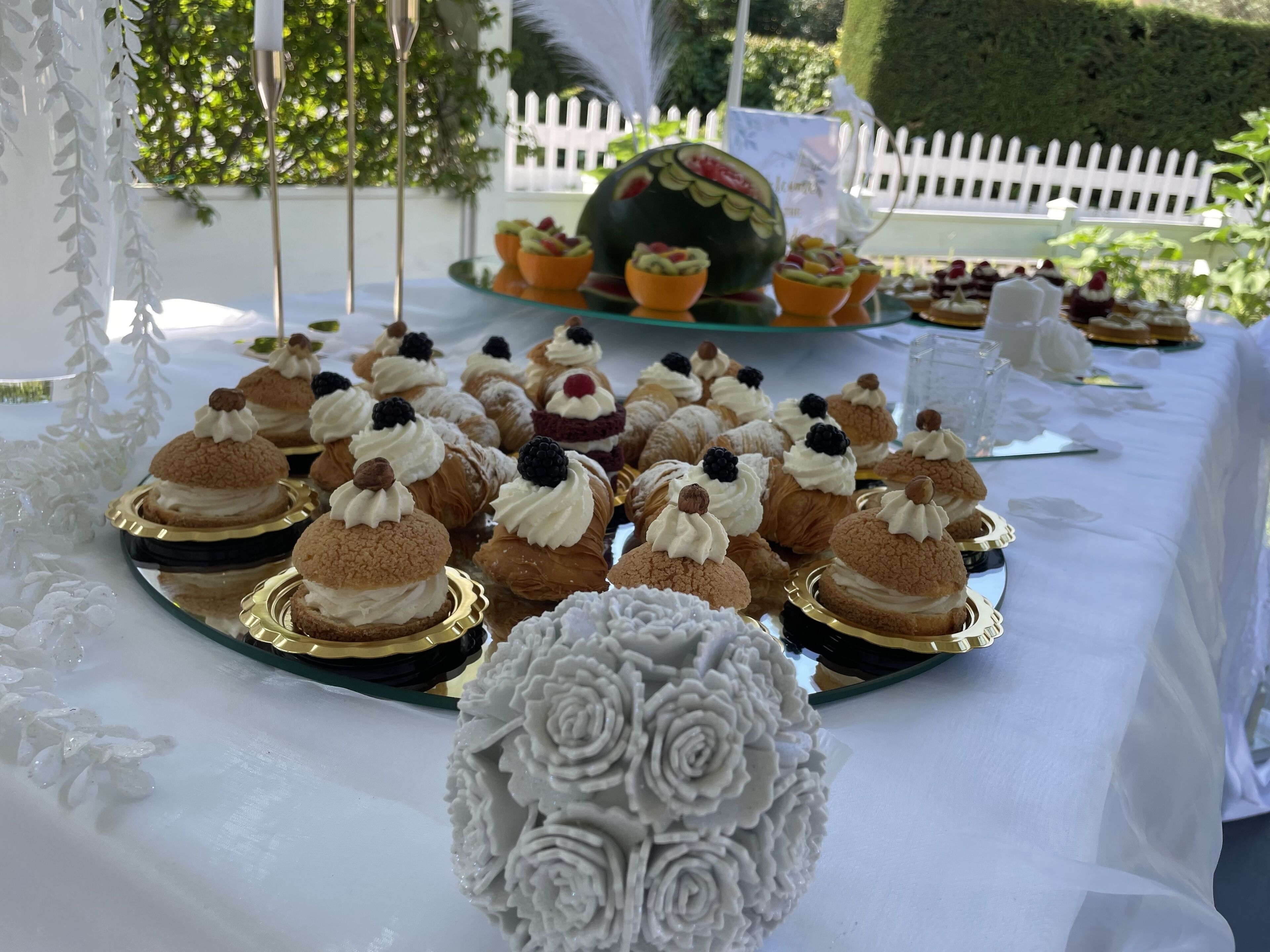 Uma mesa com diversos doces e um arranjo floral branco decorativo.