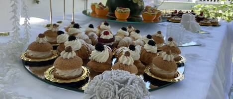Uma mesa com diversos doces e um arranjo floral branco decorativo.
