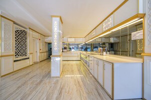 Cozinha moderna com armários brancos, piso de mármore e iluminação decorativa.