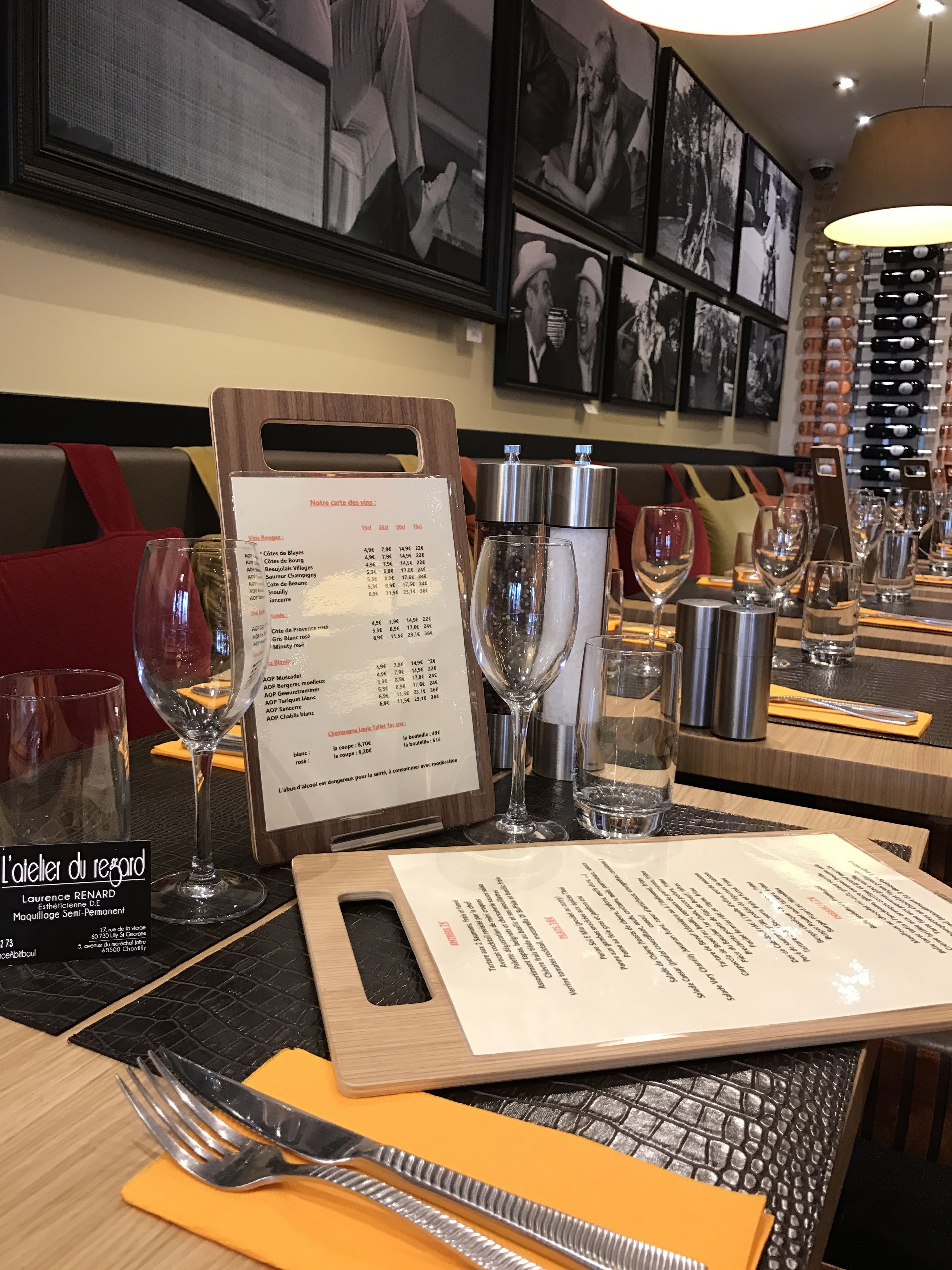 Uma mesa de restaurante com menu, copos de vinho e uma garrafa de vinho.