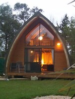 Uma cabana acolhedora de madeira, com telhado inclinado e porta de vidro.