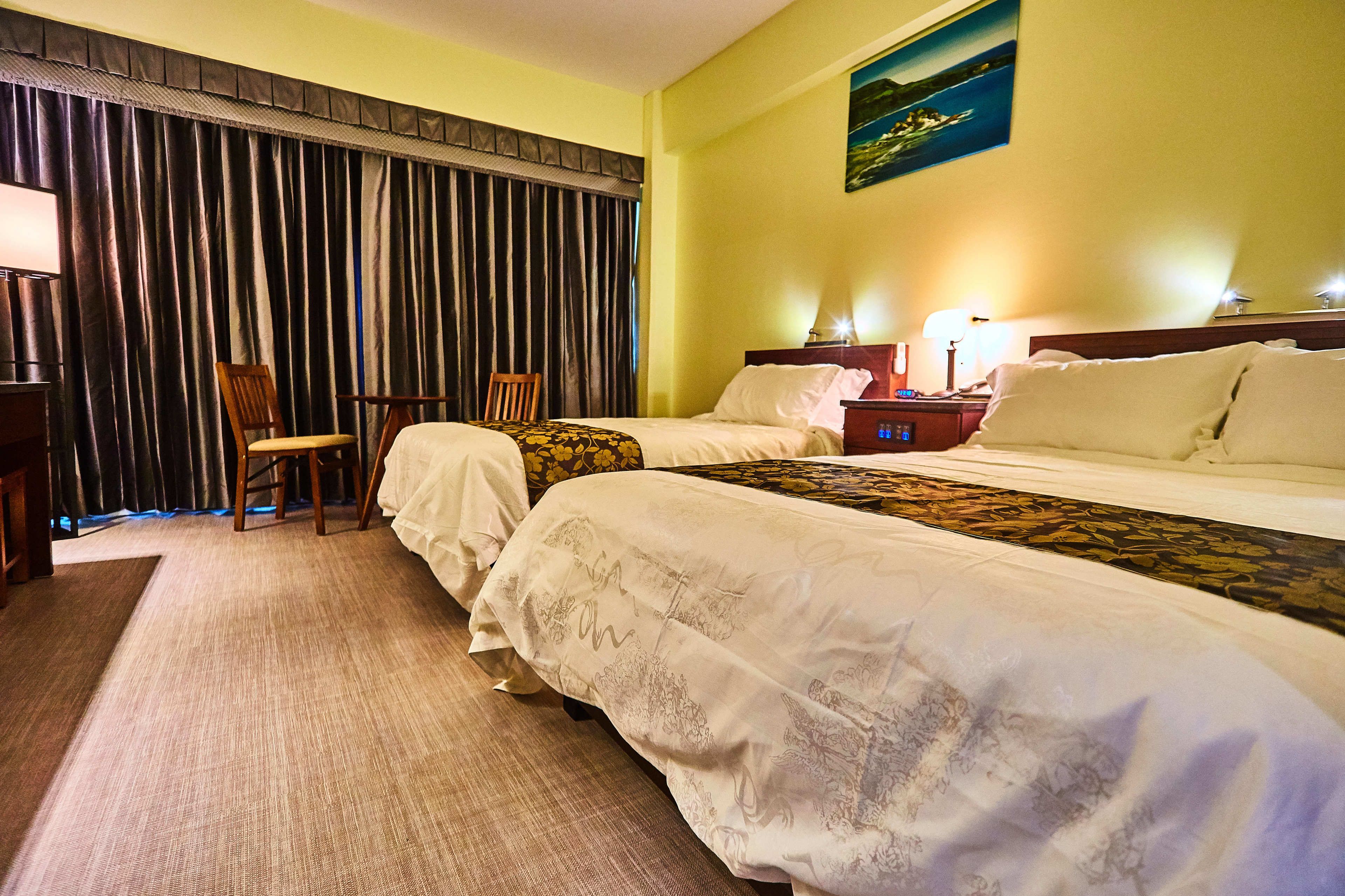 Quarto de hotel com duas camas, uma escrivaninha e uma cadeira.