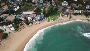 Vista aérea de uma praia com casas e mar azul cristalino.