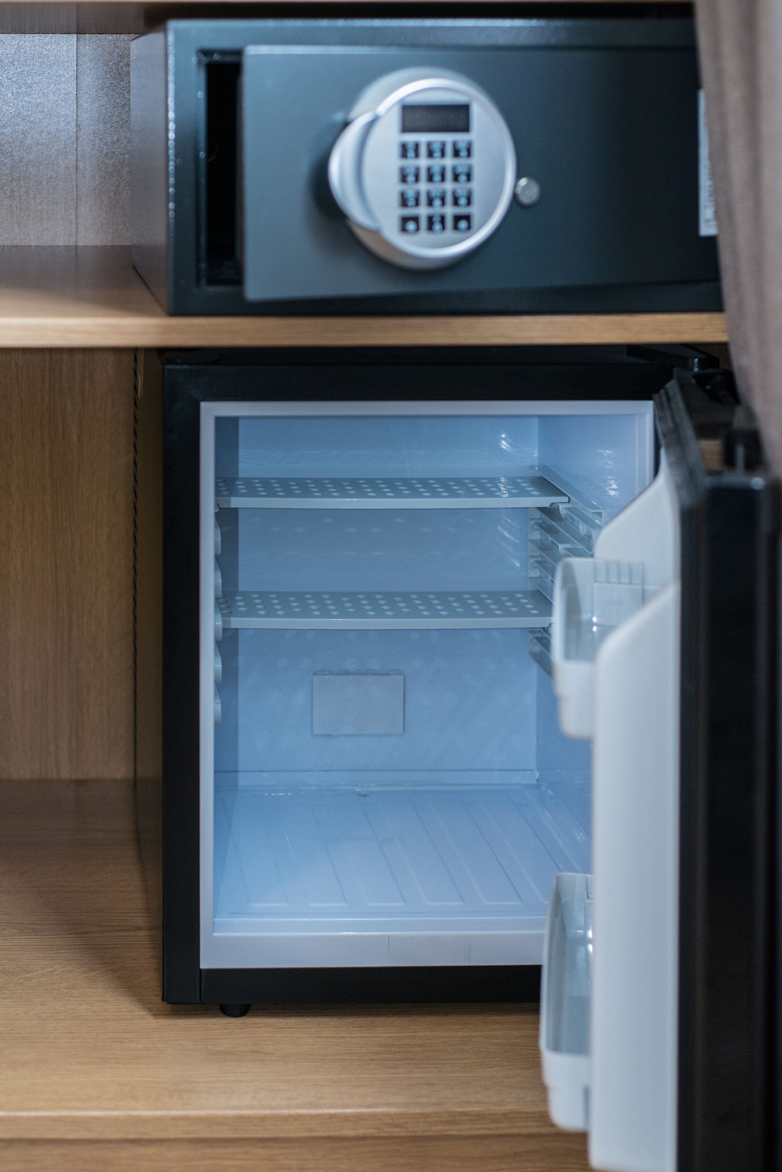Uma geladeira compacta e moderna, com fechadura digital, prateleiras embutidas e porta transparente.