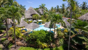 Resort com piscina rodeada por palmeiras e estruturas de telhado de palha.