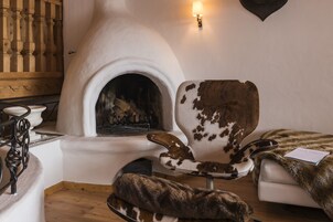 Um quarto acolhedor com lareira, uma poltrona confortável e um cobertor de pele.