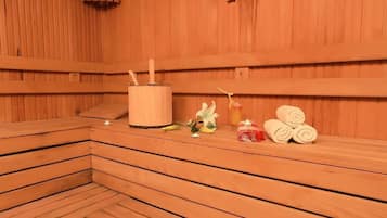 Uma sauna de madeira com bancos, um recipiente de madeira, velas e toalhas.