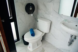 Casa de banho com sanita, lavatório e dispensador de papel.