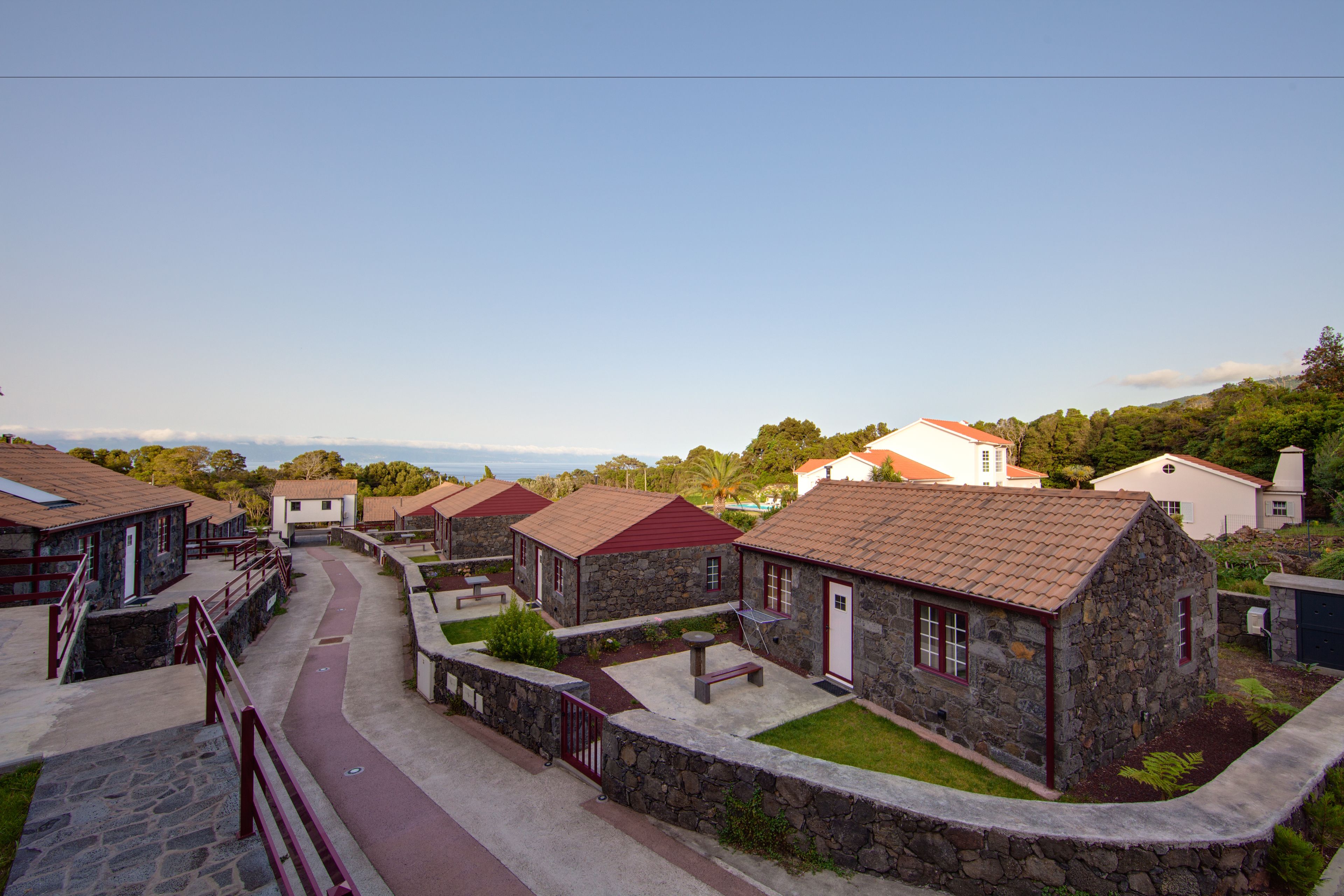Uma vila costeira com edifícios de pedra, um passeio pavimentado e vista para o mar.
