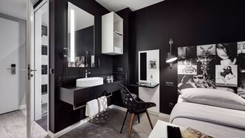 Casa de banho moderna com um espelho grande, lavatório branco e toucador preto.
