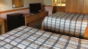 Quarto de hotel com duas camas, televisão, cómoda de madeira e espelho.