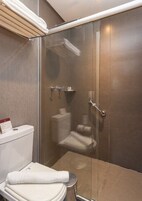 Um banheiro moderno com box de vidro, vaso sanitário e pia.