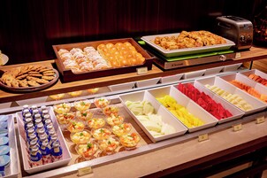 Buffet com diversos itens, incluindo doces, frutas e bebidas.