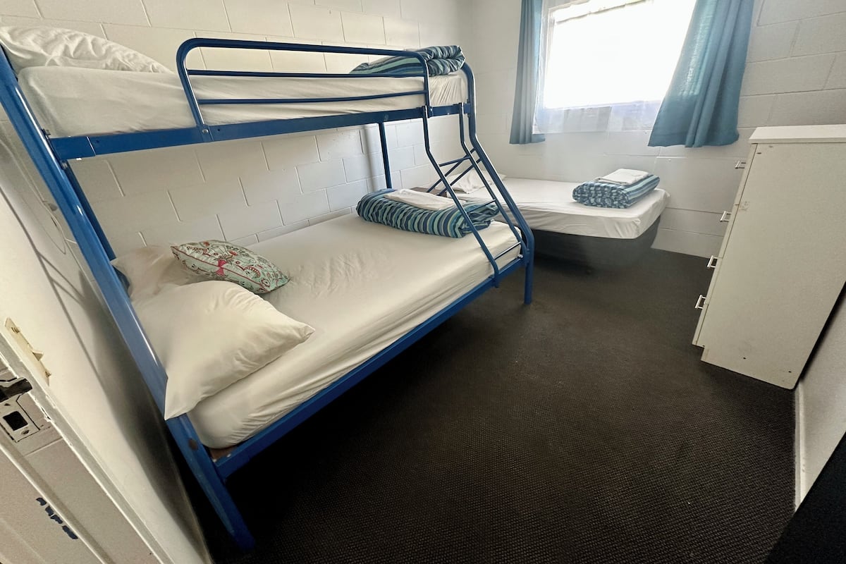 Quarto com beliche, escrivaninha e armário.