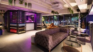 Uma área de estar moderna com um sofá confortável, um bar com prateleiras cheias de garrafas e plantas penduradas.