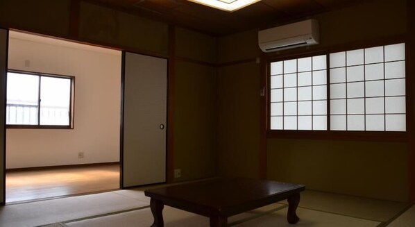 Um quarto japonês tradicional com tatames, uma porta deslizante, um painel shoji e uma pequena mesa.