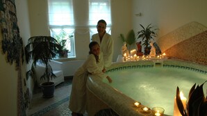 Uma área de piscina interior tranquila, com chão em azulejo, um banco e velas.