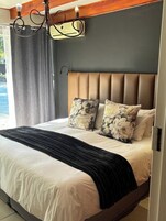 Quarto com uma cama grande, cabeceira e janela com cortinas.