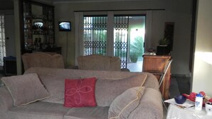 Uma sala de estar com sofá, cadeiras, televisão e uma varanda com vista.